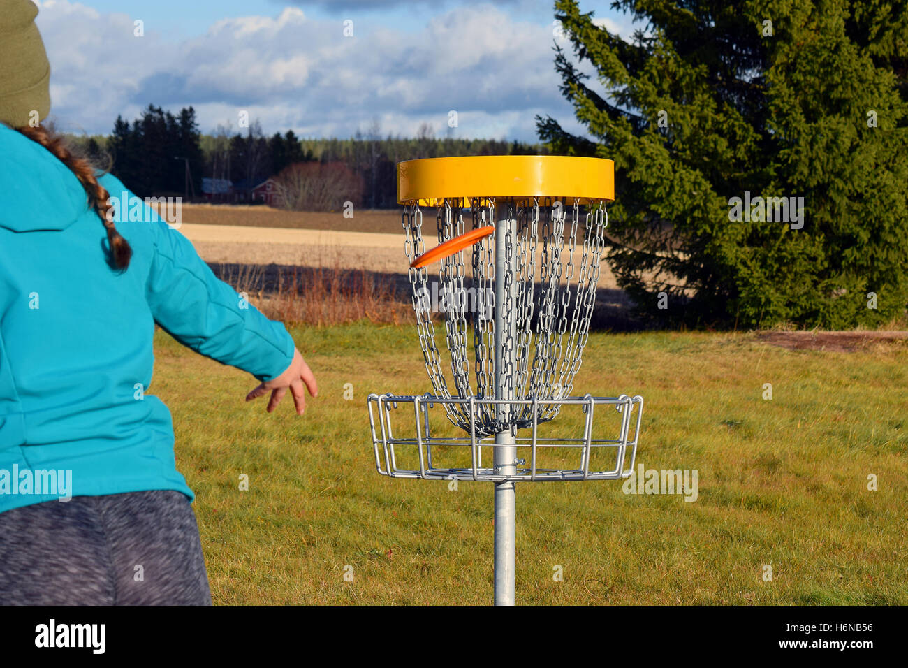 Young woman throws disc to target on disc golf course Stock Photo - Alamy