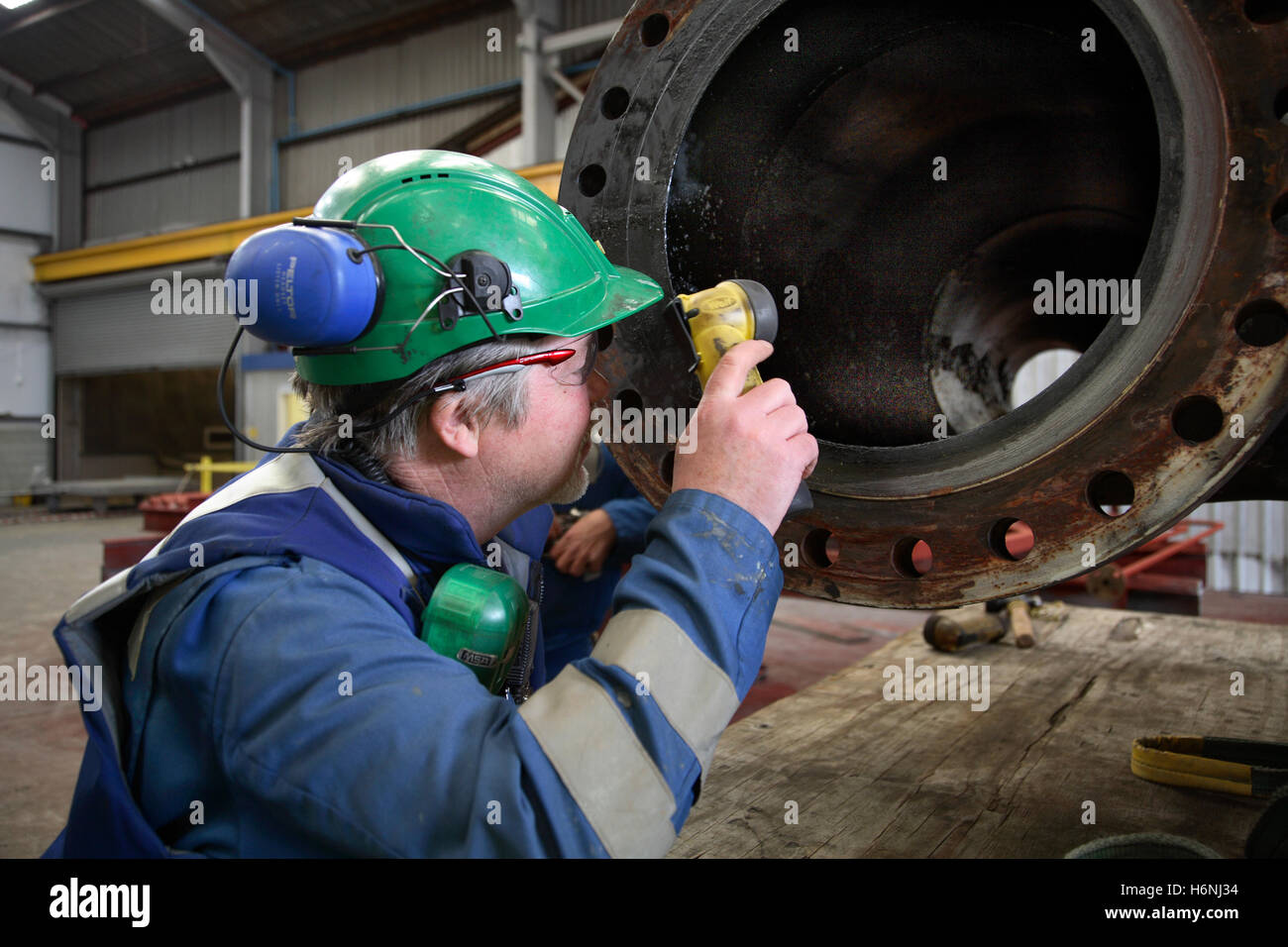 An engineer in a petrochemical maintenance facility inspects pipe ...