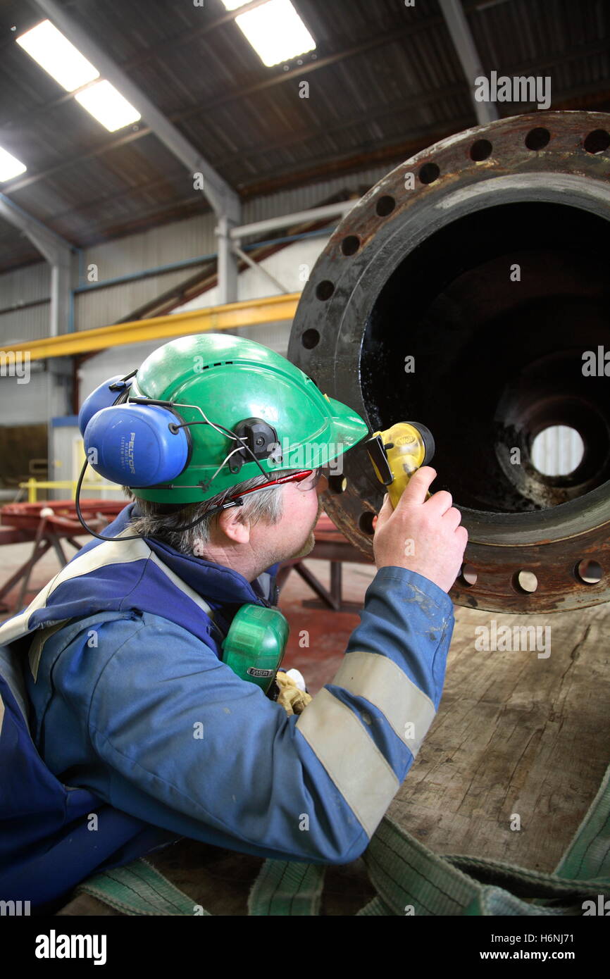 An engineer in a petrochemical maintenance facility inspects pipe ...