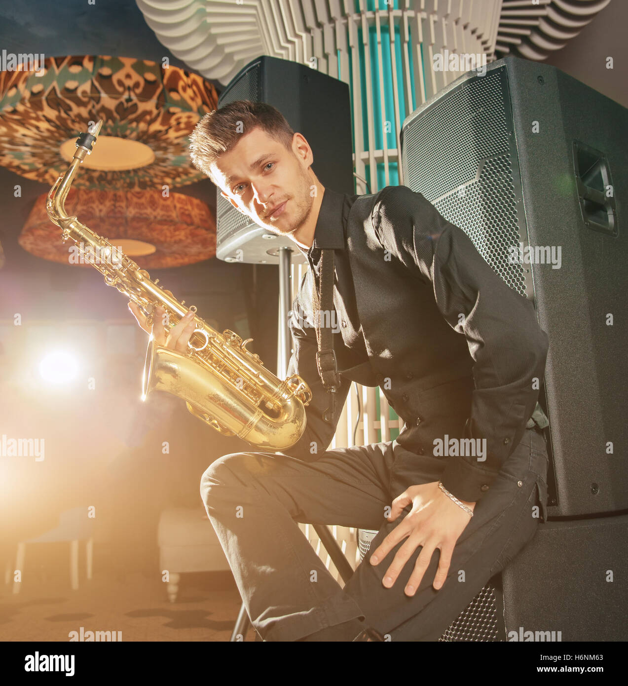 Young man sitting and holding saxophone Stock Photo - Alamy