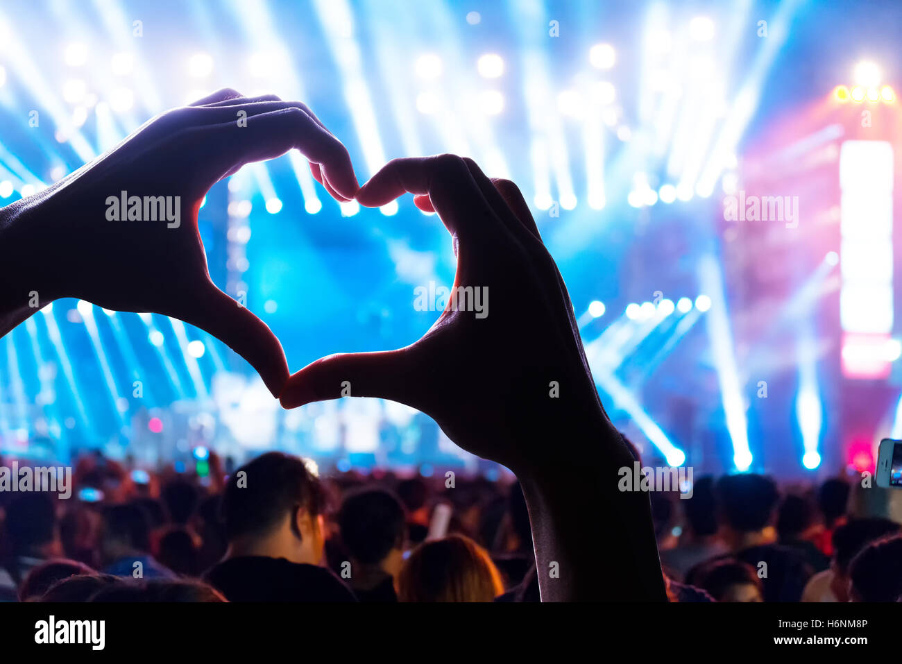 Silhouette of a heart shaped hands and crowd of Audience at live ...