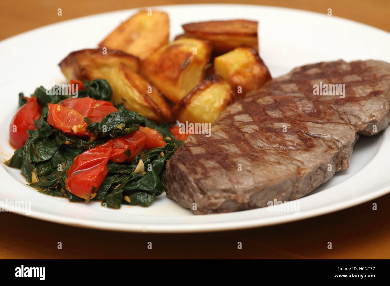 Rump steak with fried potatoes and leaf spinach Stock Photo - Alamy