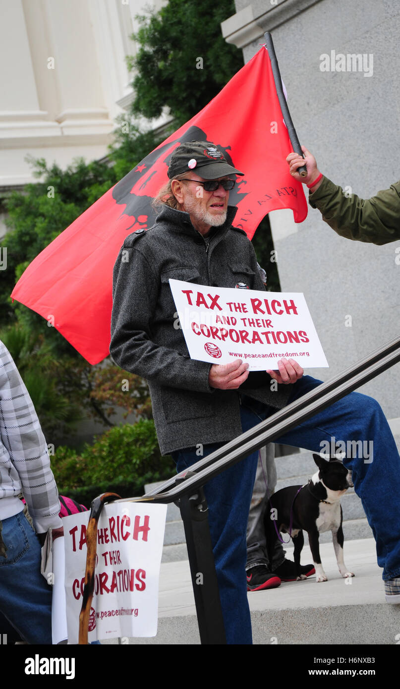 A activist holding a sign reading "tax the rich and their corporations ...