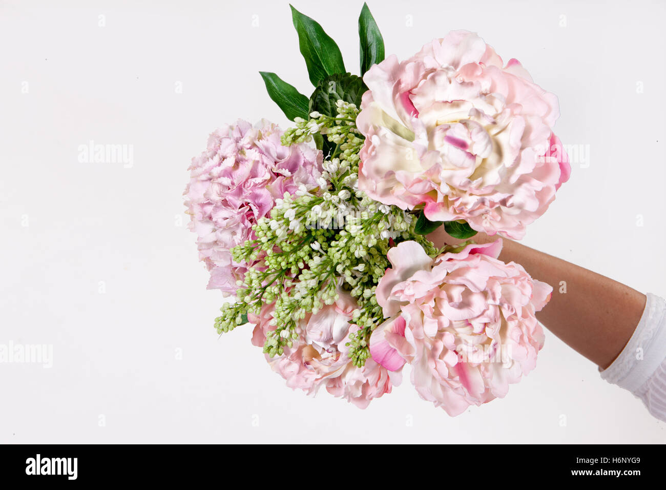 Hand holding a bouquet of different flowers on an isolated studio ...
