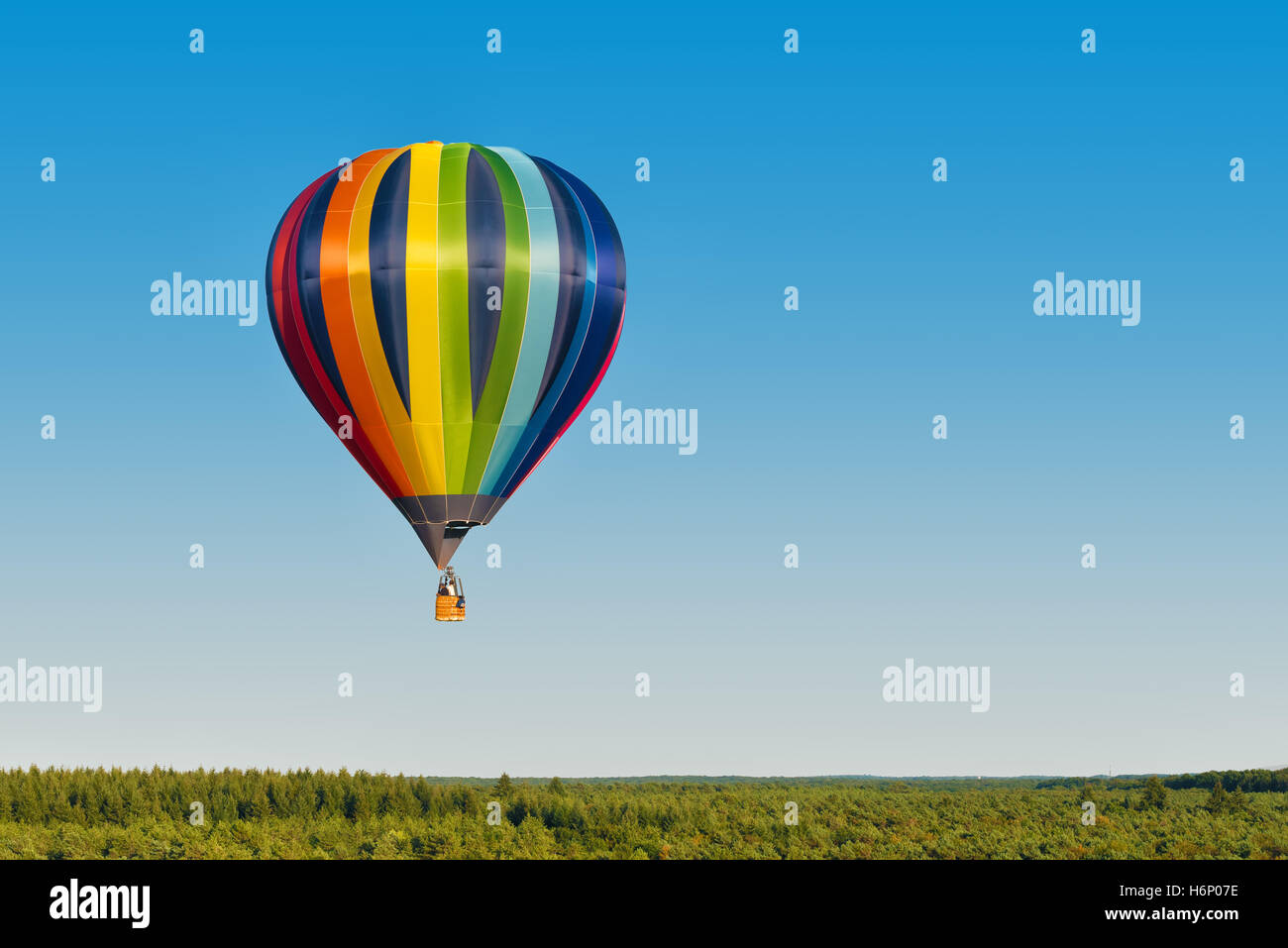 Aerial view of a multicolored hot air balloon flying over a forest ...