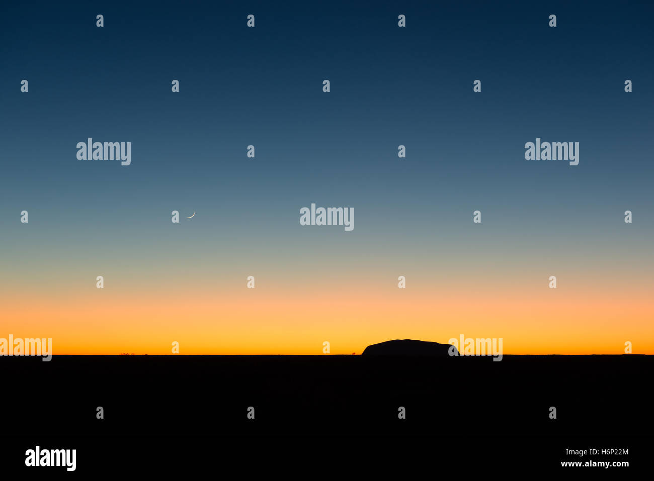 Silhouette of Uluru with clear sky and crescent moon at sunrise Stock ...