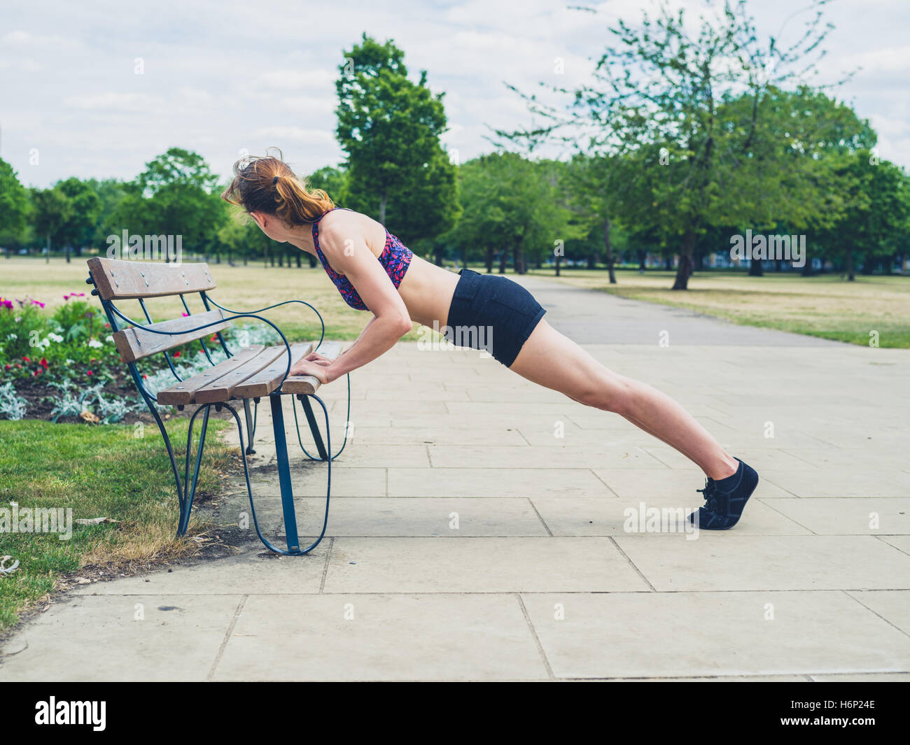A fit and athletic young woman is performing a plank exercise on a ...