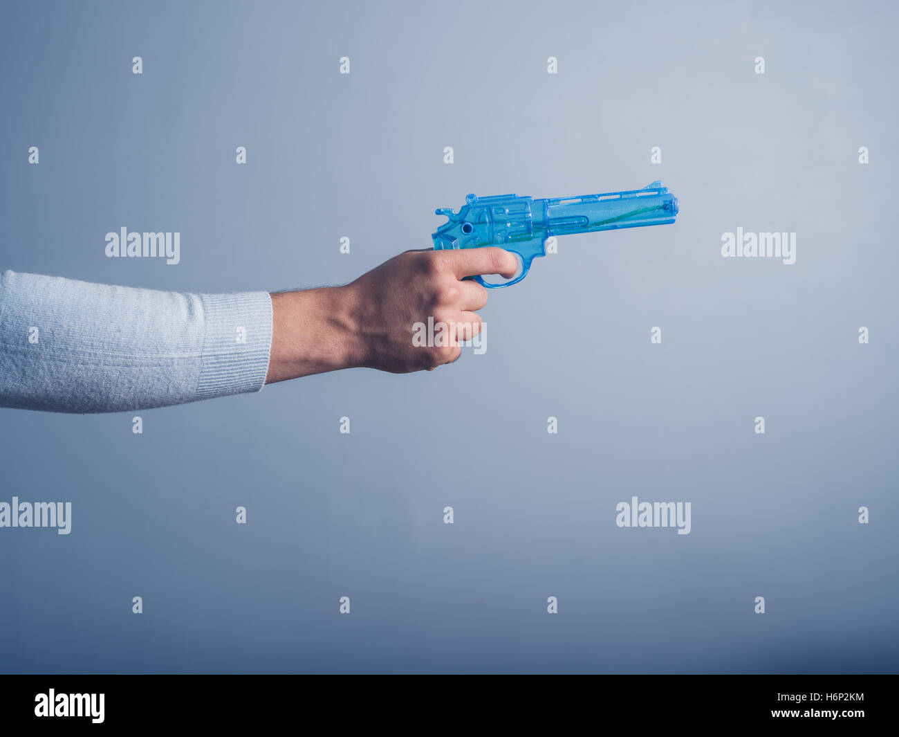A male hand is holding a blue water pistol and is aiming it Stock Photo ...