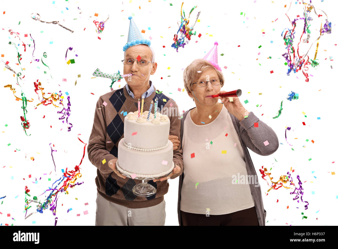 Senior couple with favor horns and party hats celebrating a birthday ...