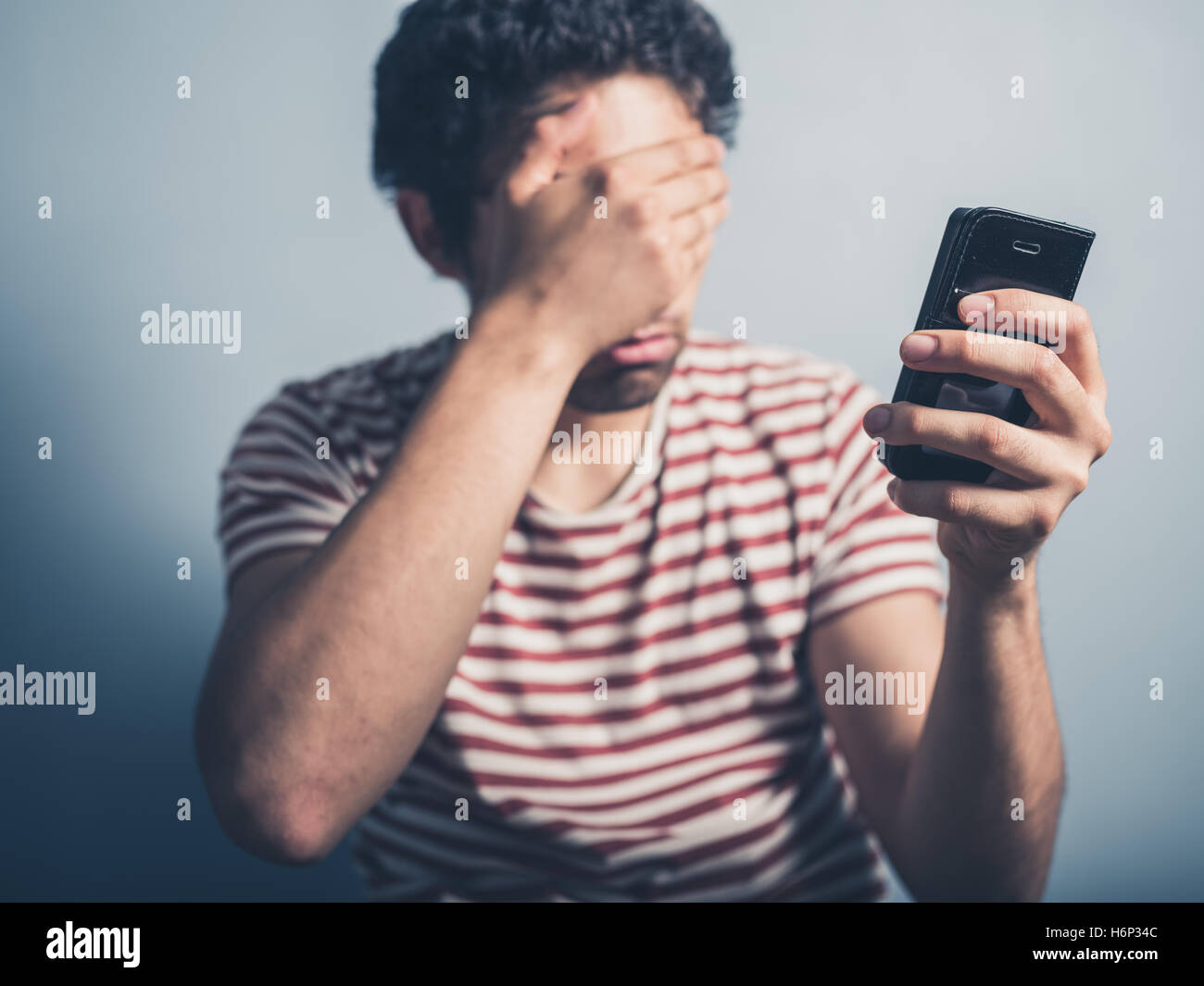 A shocked young man is using a smart phone Stock Photo - Alamy