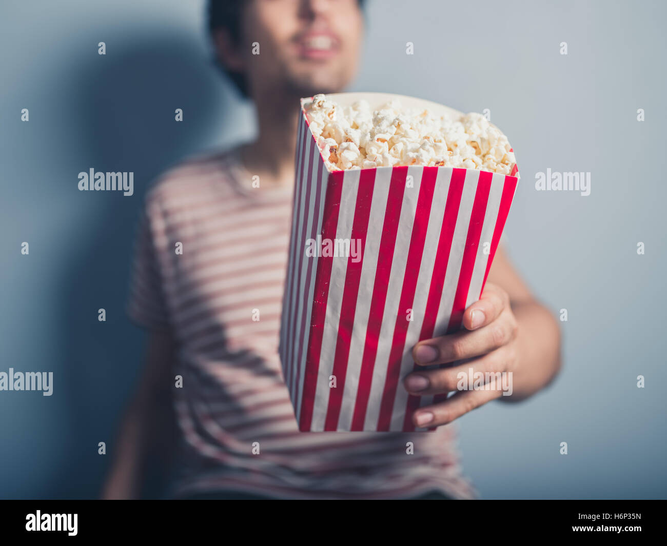 A young man is offering popcorn Stock Photo - Alamy
