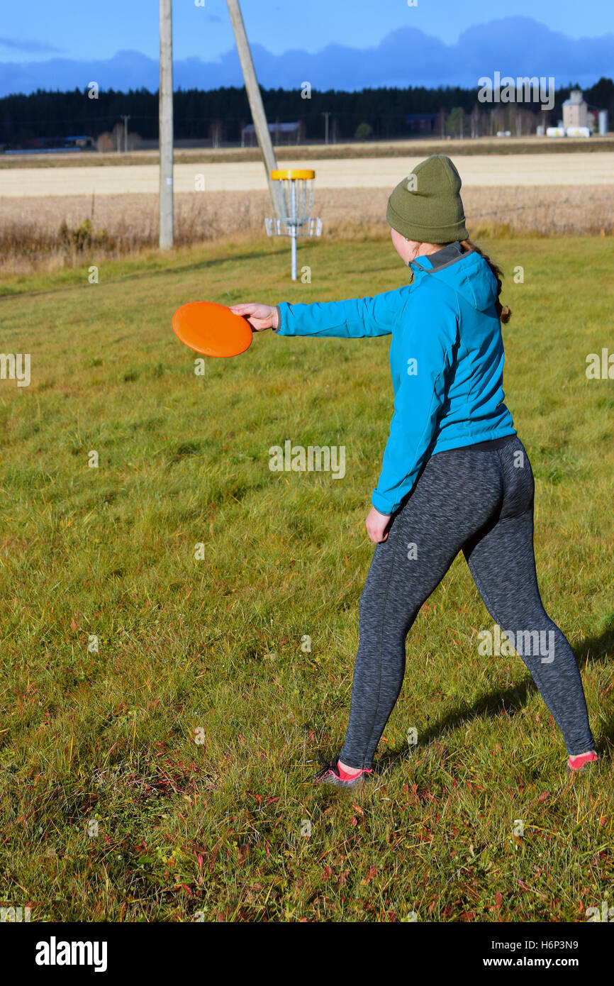 Young woman throwing disc to target on disc golf course Stock Photo - Alamy