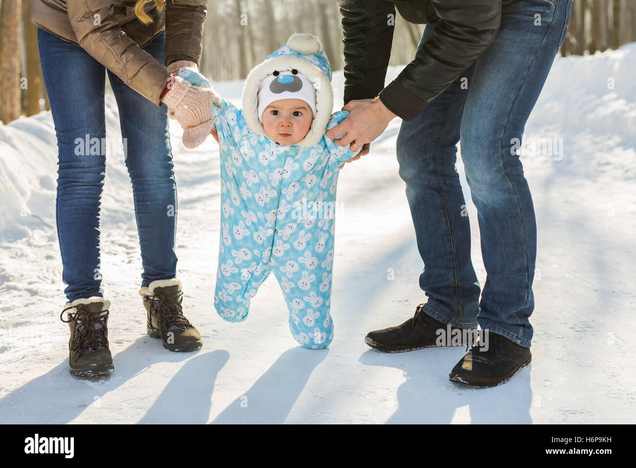 First steps. Little baby learning to walk. Mother and father with ...