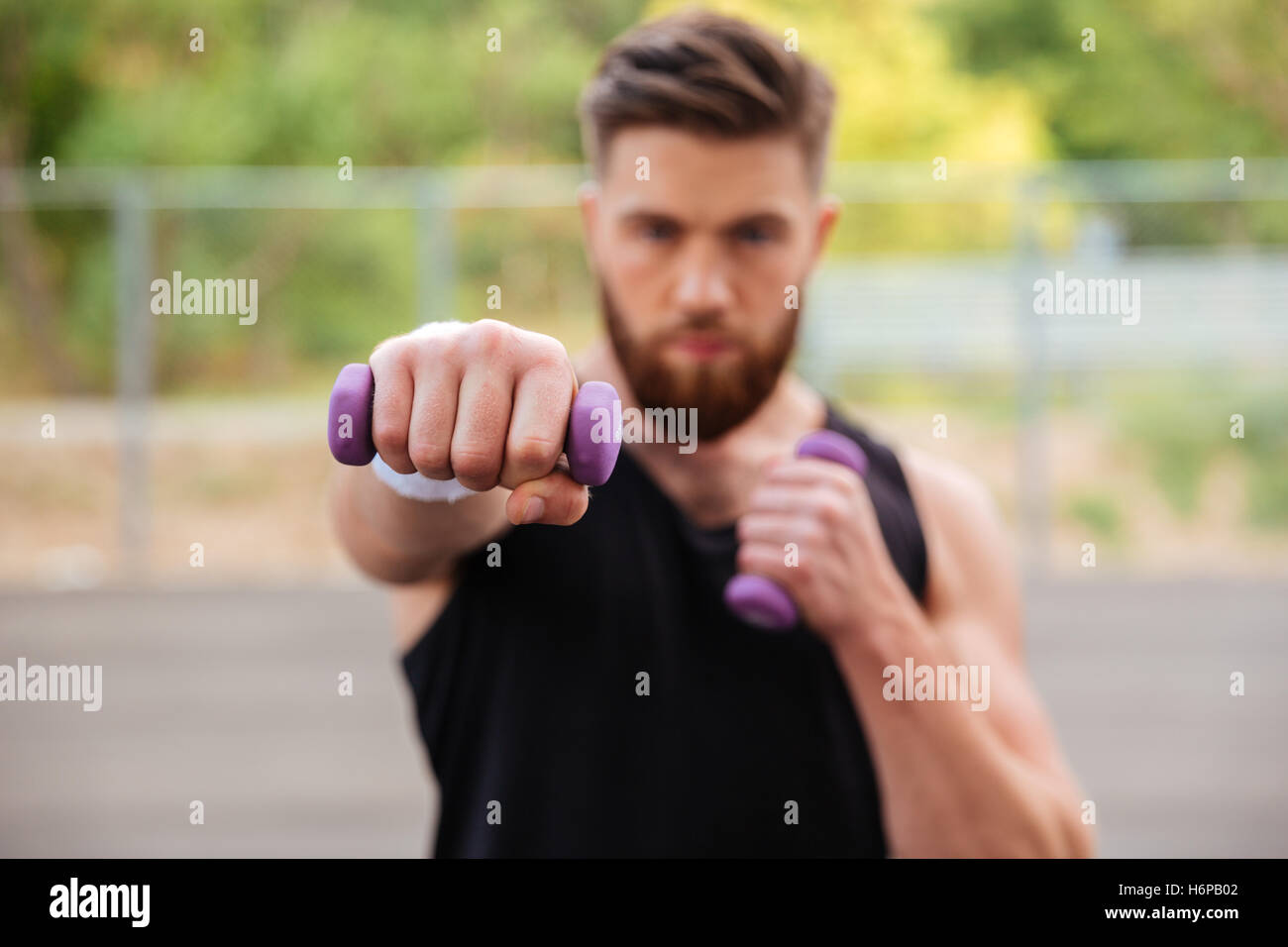 Handsome bearded sports man working out with small dumbbells outdoors ...