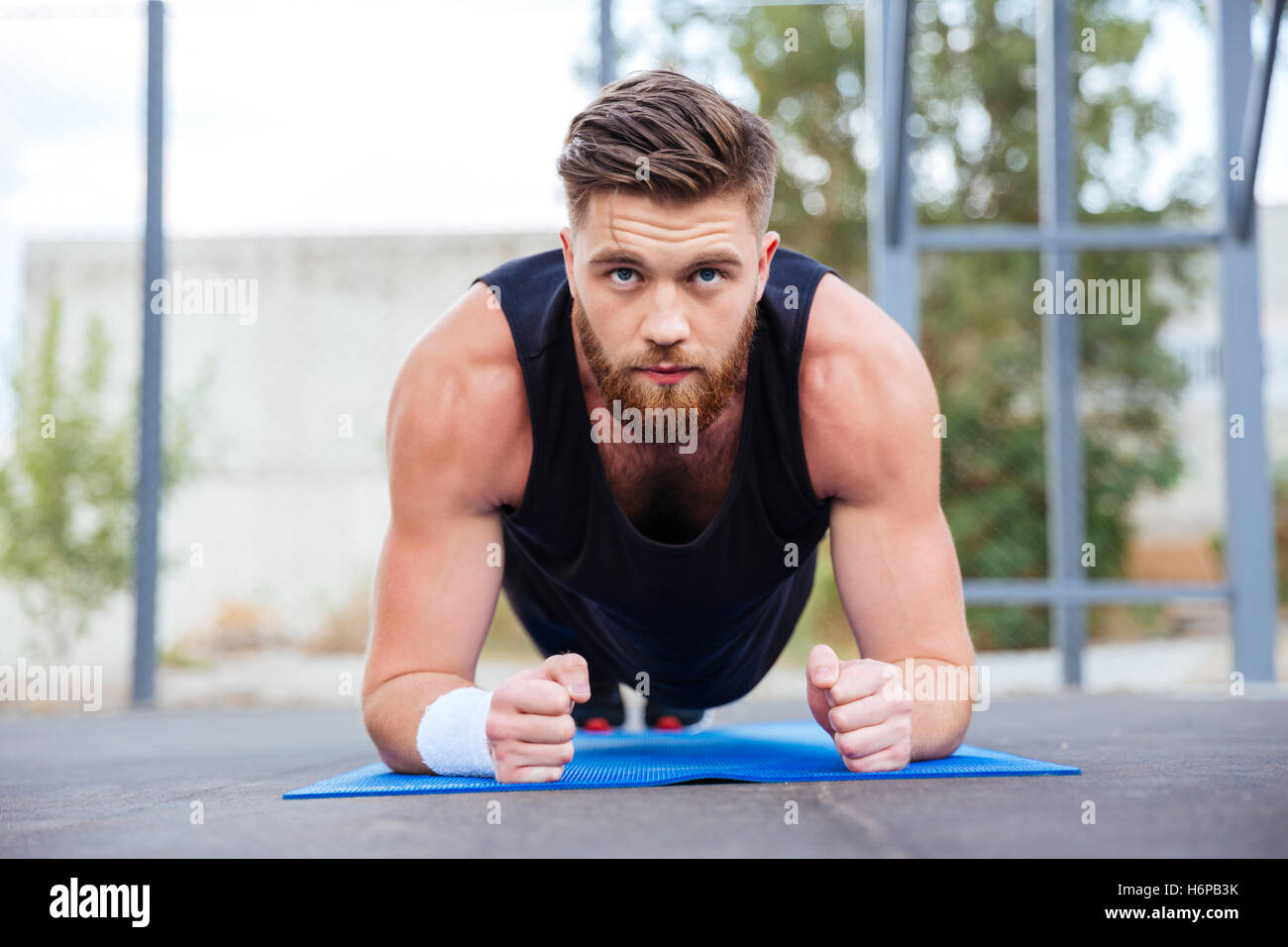 Young strong sportsman doing plank exercise on blue fitness mat during ...