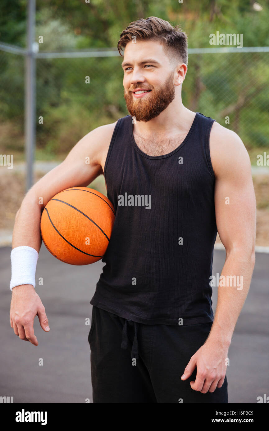 Cheerful happy basketball player standing with ball outdoors Stock ...