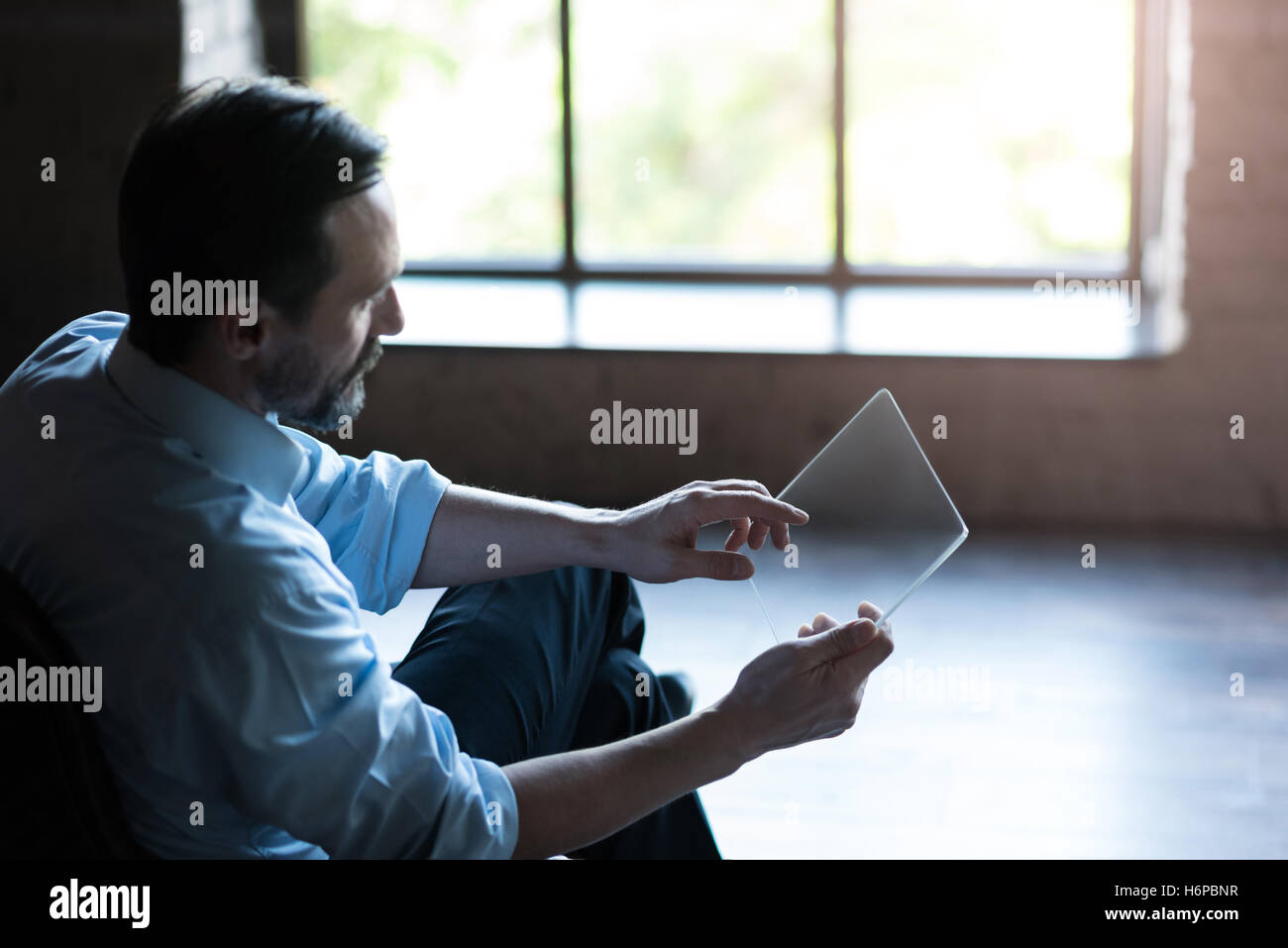 Serious concentrated man sitting against the window Stock Photo - Alamy