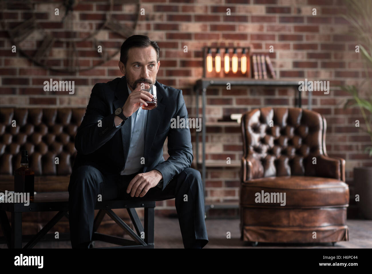 Handsome serious man taking a sip of whisky Stock Photo - Alamy