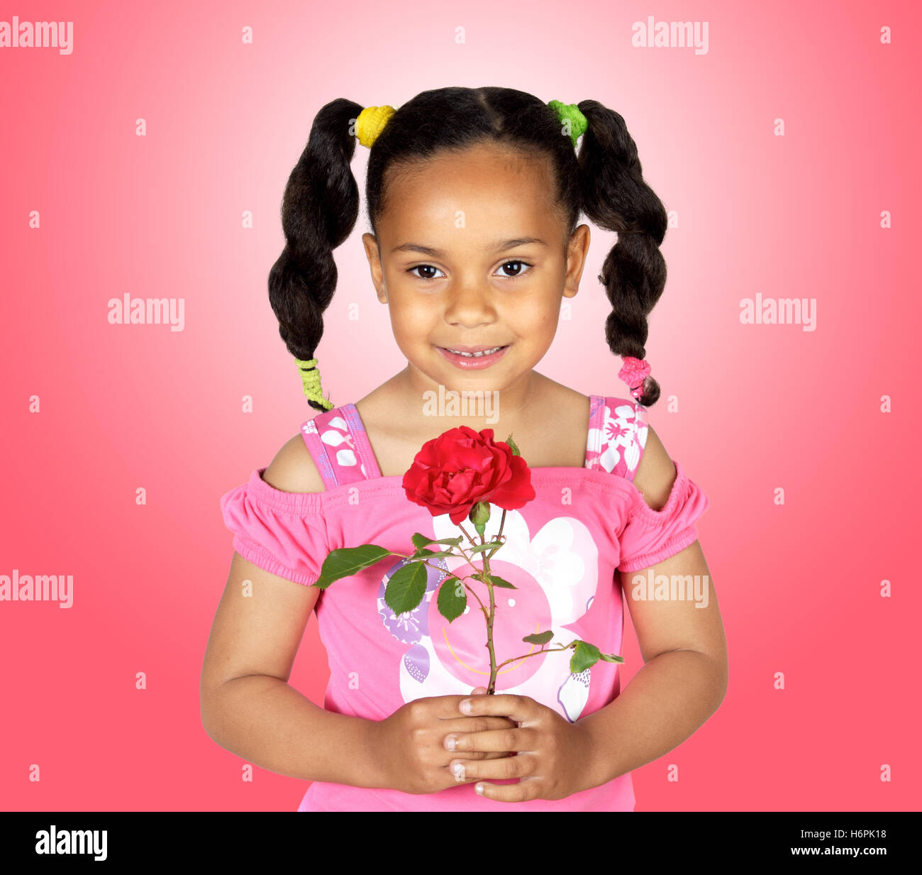 Smiling little girl with a red rose for gift on a over pink background ...