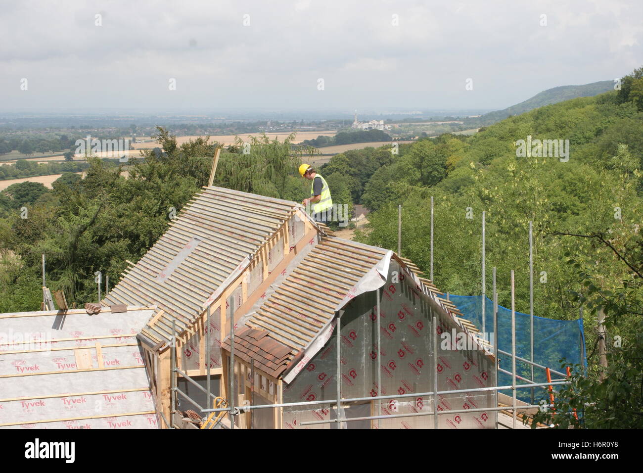 A Roofer Nails Battens To The Roof Of A Timber Frames House On An Oxfordshire Hillside Self
