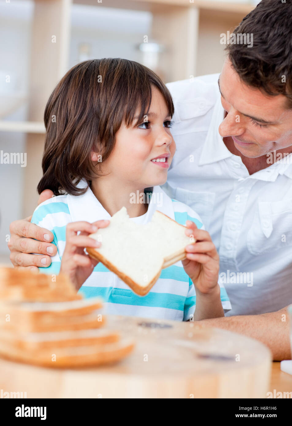 Adorable little boy and his father eating bread in the kitchen Stock ...