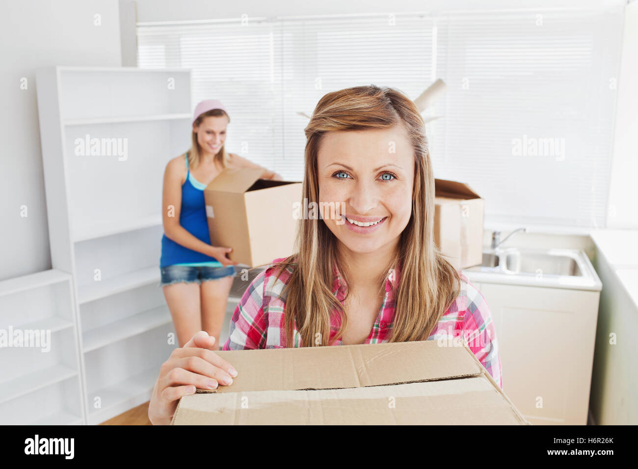 Two women carrying boxes at home in their new location Stock Photo - Alamy