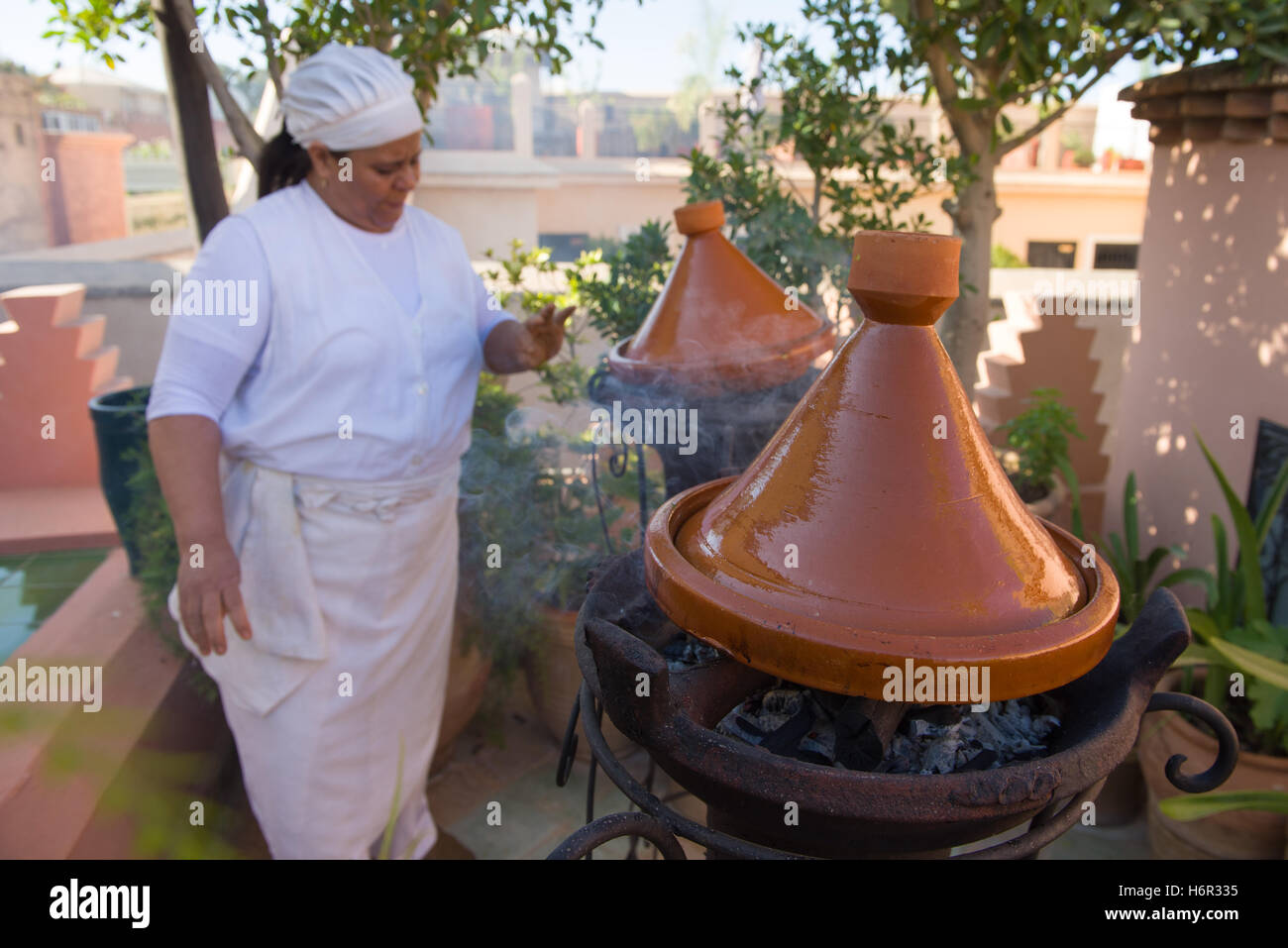 Fouzia, a traditional dada (traditional female chef) at Dar Les Cigognes, cooking tagines over ...