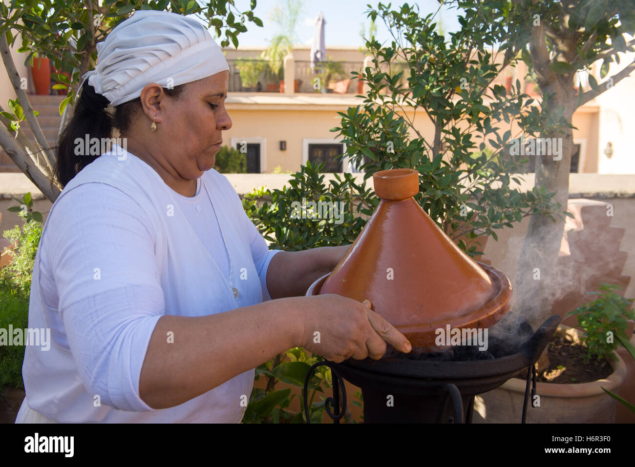 Fouzia, a traditional dada (traditional female chef) at Dar Les Cigognes, cooking a tagine over ...