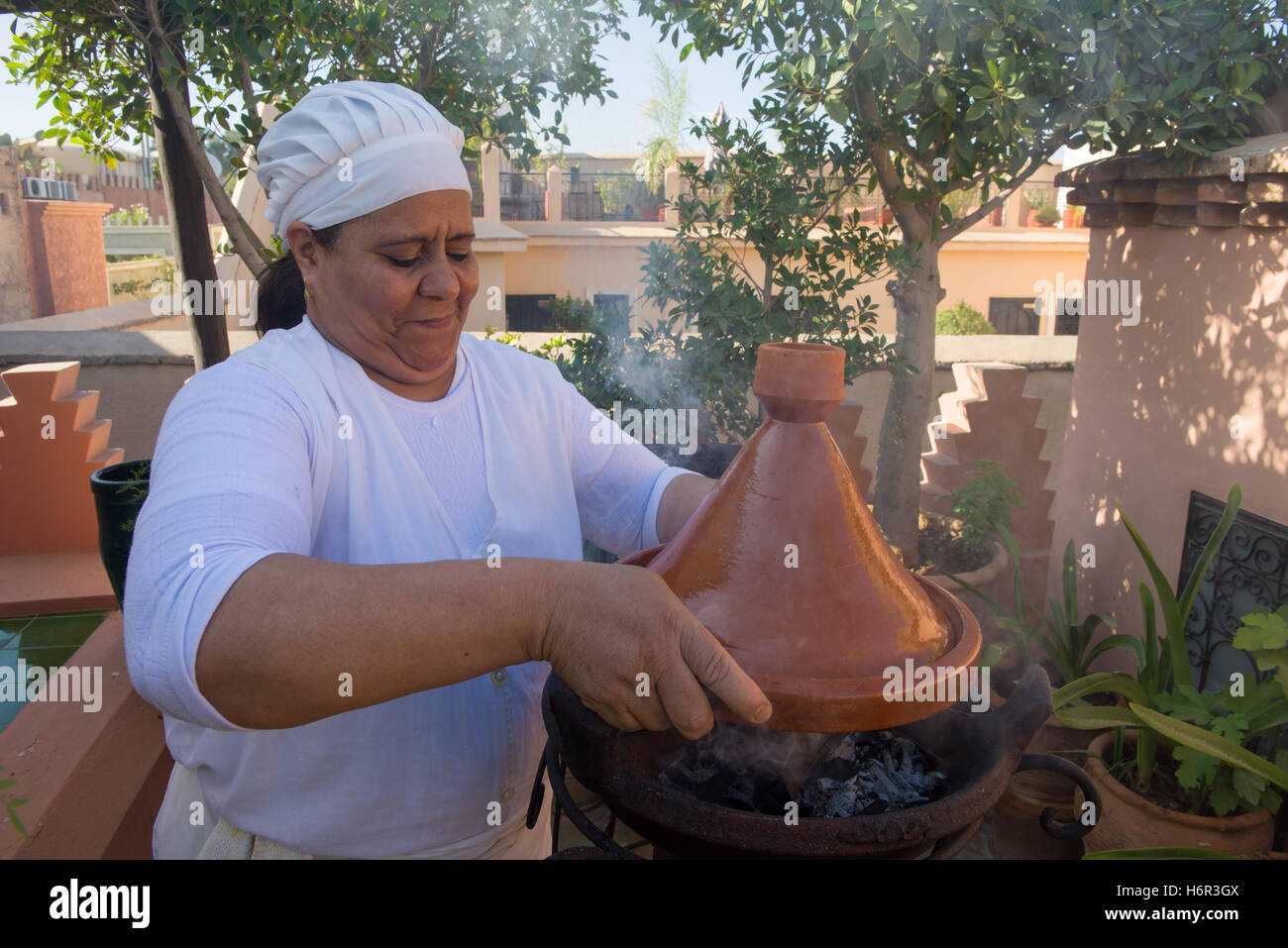 Fouzia, a traditional dada (traditional female chef) at Dar Les Cigognes, cooking a tagine over ...