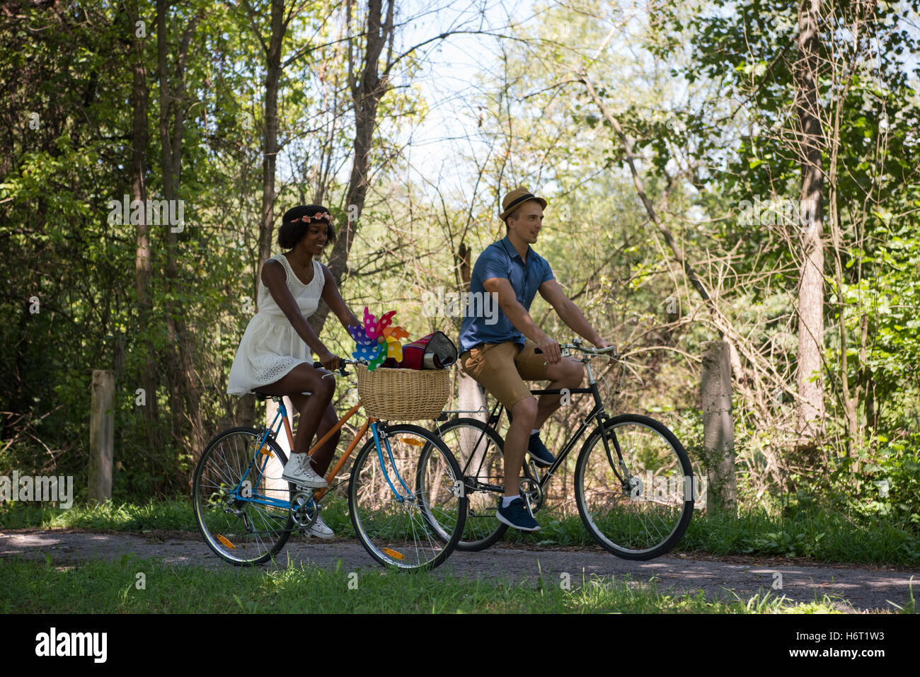 a young man and a beautiful African American girl enjoying a bike ride ...