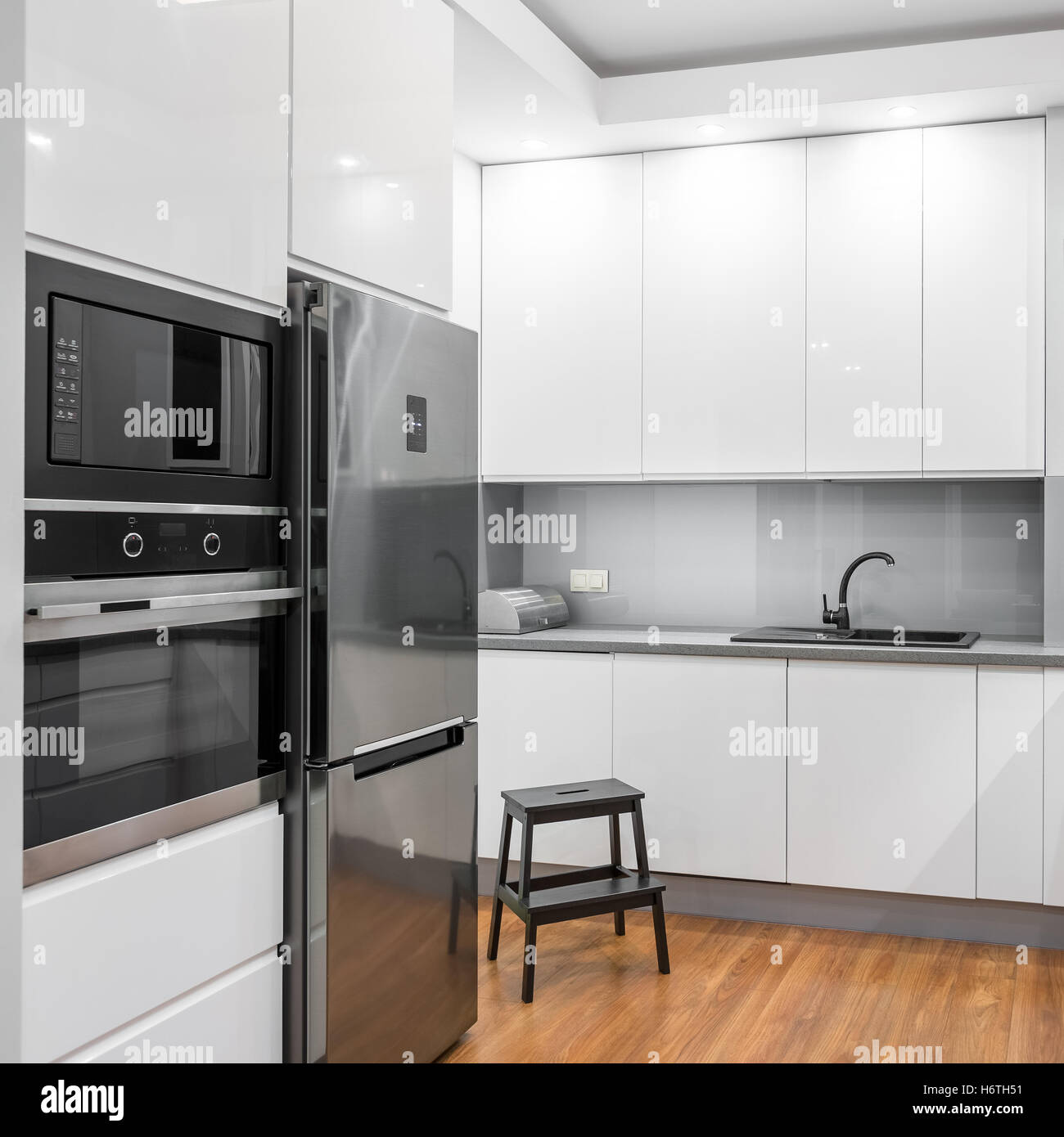 White high-gloss kitchen with silver fridge, oven and microwave Stock ...
