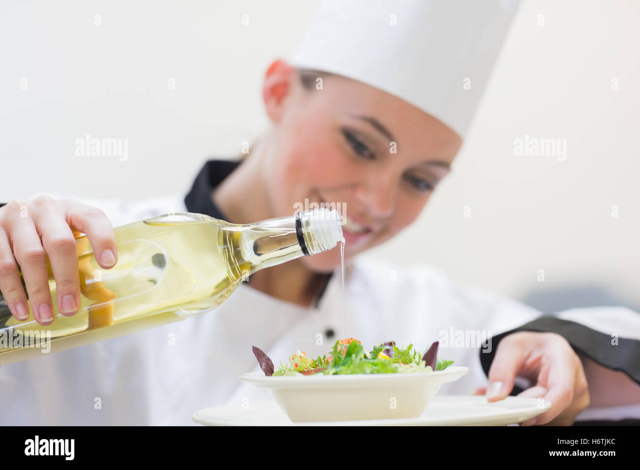 Smiling woman chef dressing a salad in the kitchen Stock Photo - Alamy