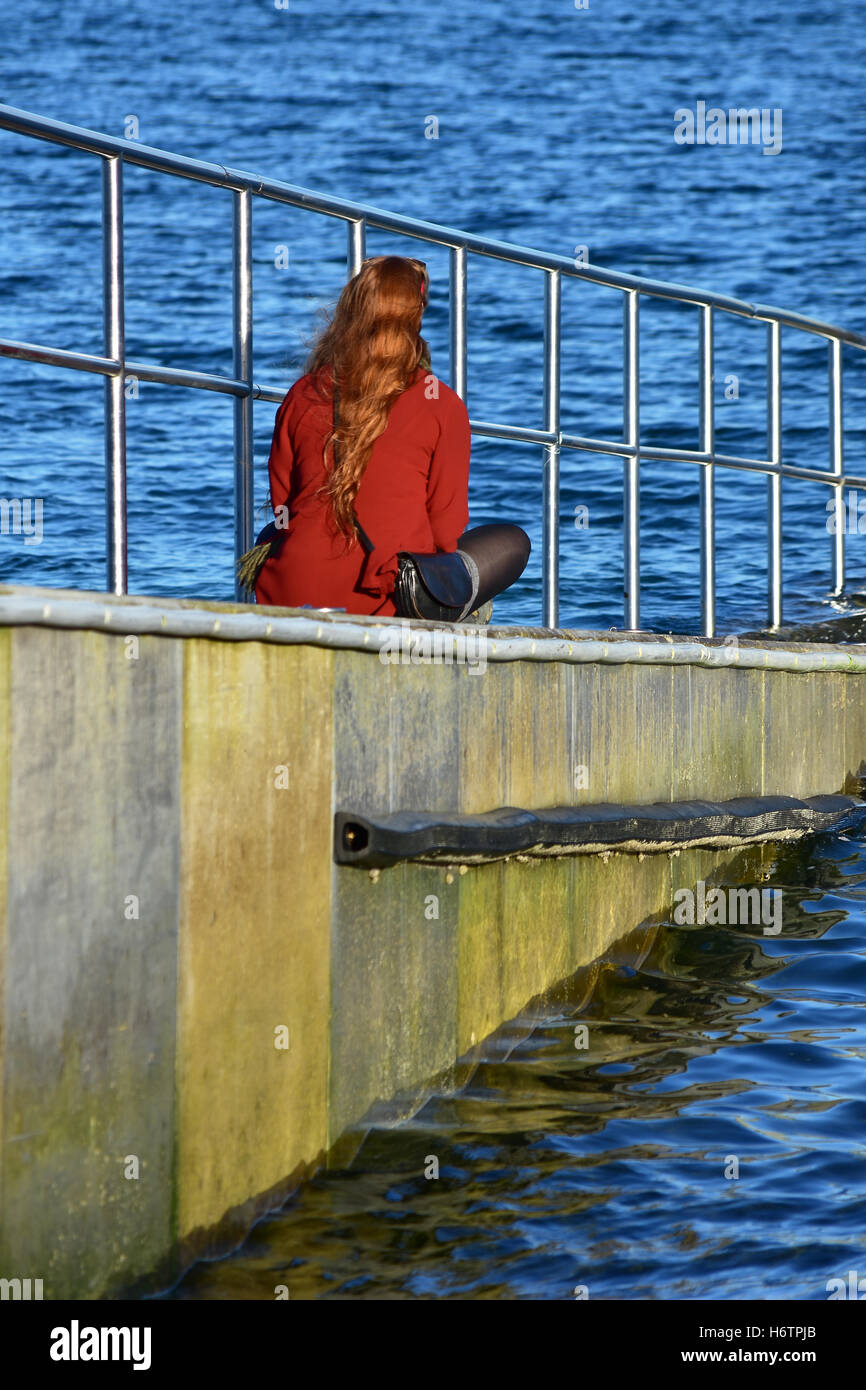 Woman meditating on the narrow side of a boat ramp surrounded by water ...