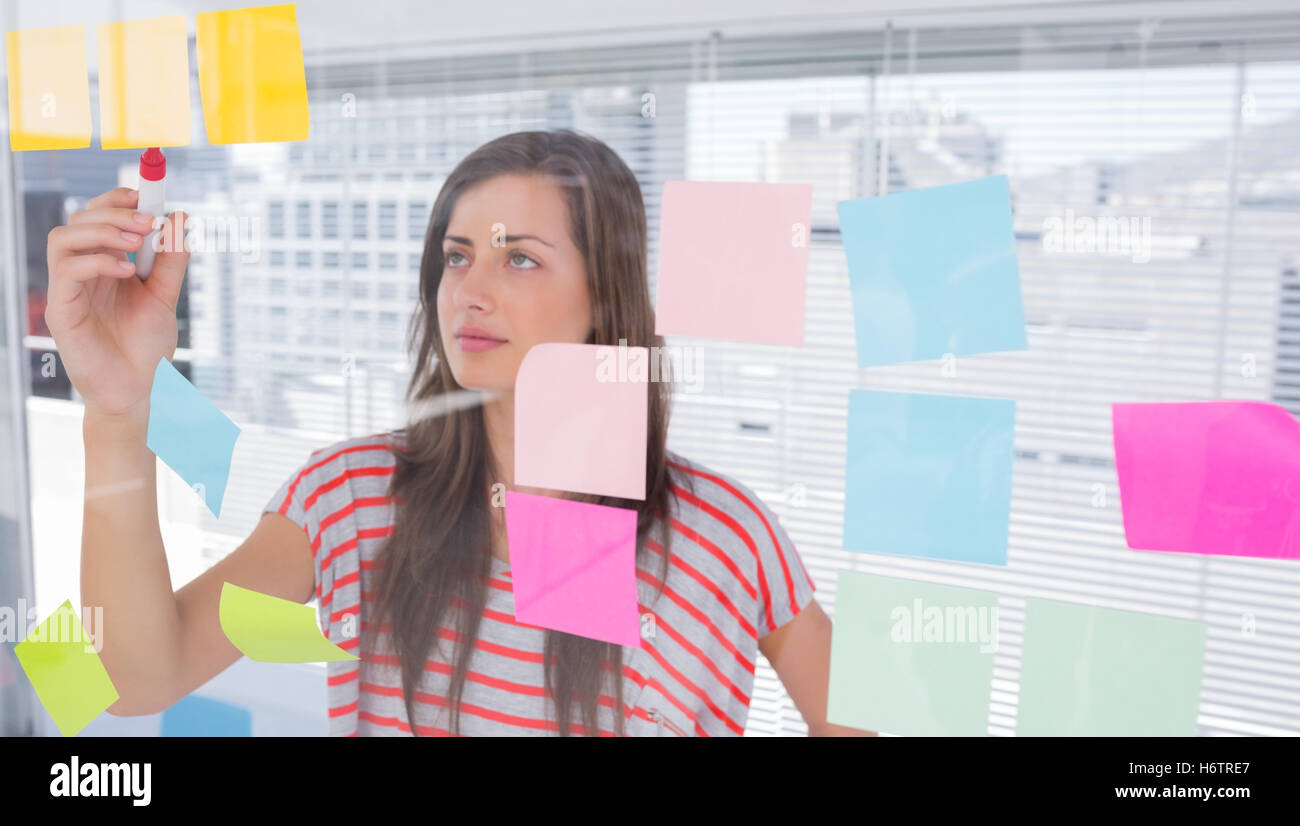Young woman writing on sticky note in creative office Stock Photo - Alamy