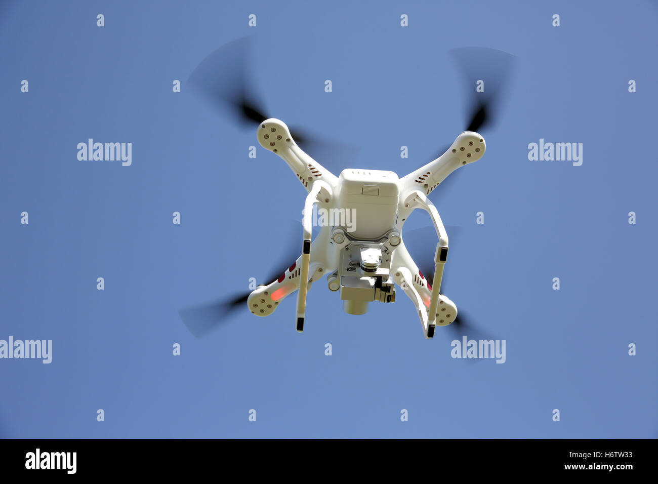 White drone quad copter with flying in the clear blue sky Stock Photo ...