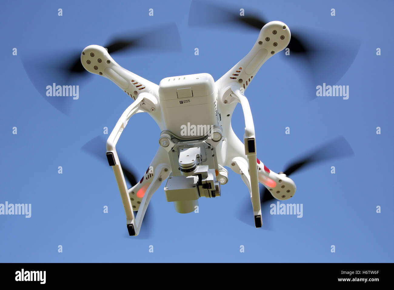 White drone quad copter with flying in the clear blue sky Stock Photo ...