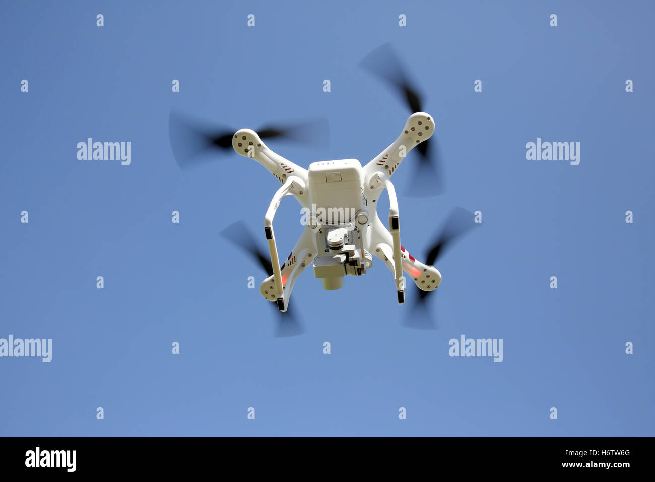 White drone quad copter with flying in the clear blue sky Stock Photo ...