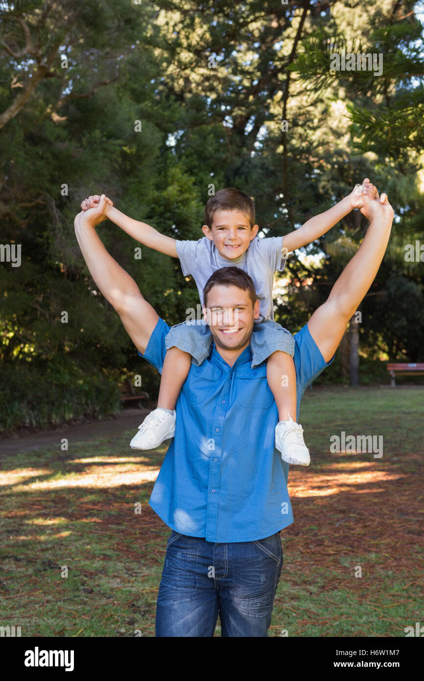 Father giving son piggy back and stretching out their arms smiling at ...