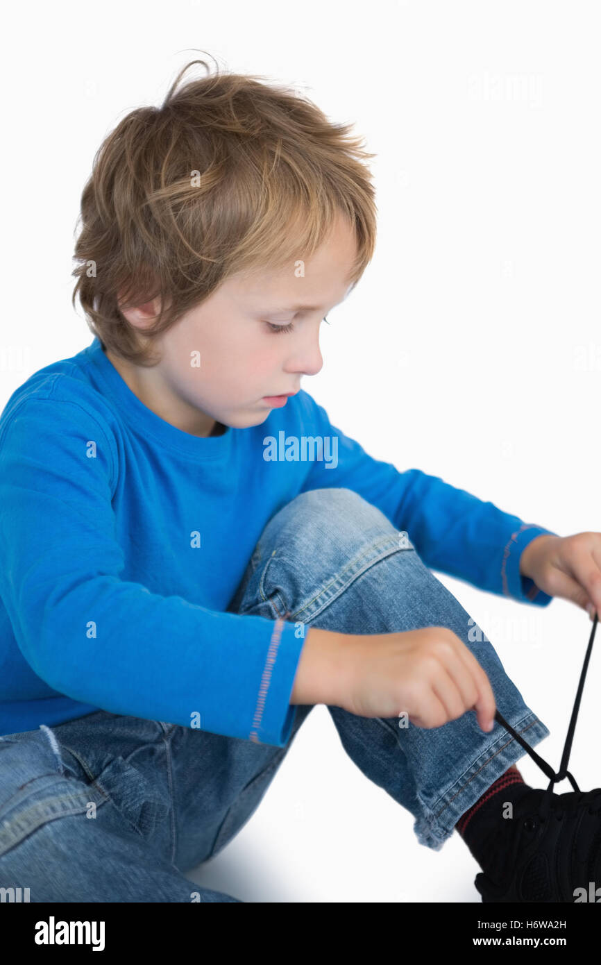 Little boy binding laces over white background Stock Photo - Alamy