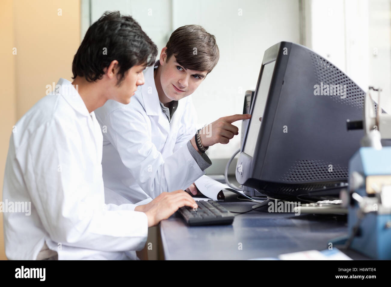 Student pointing at something on a monitor to his classmate in a ...