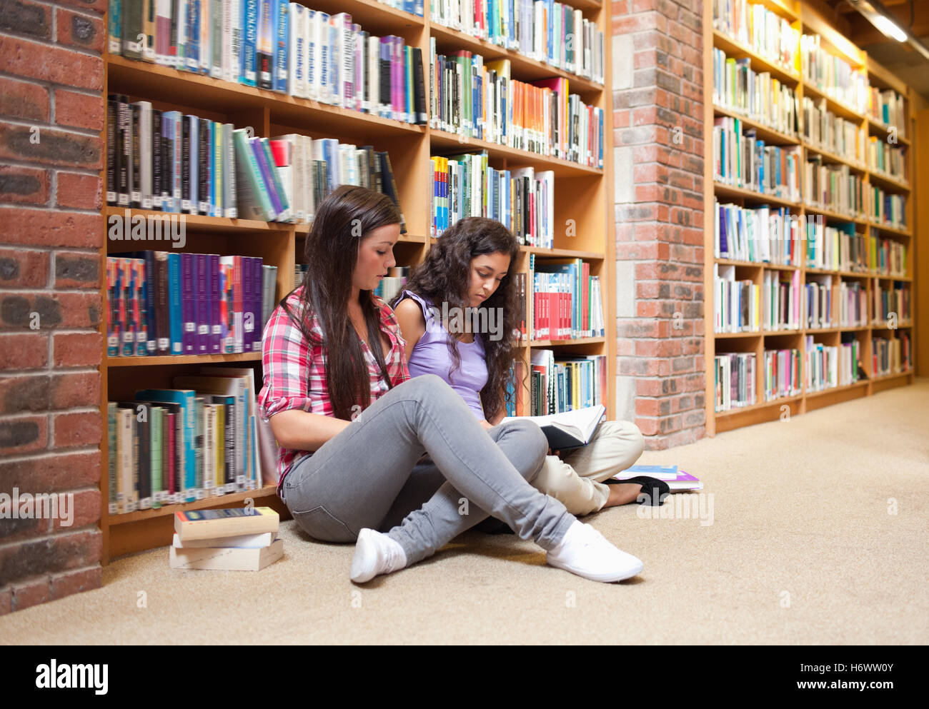 Female students with a book in a library Stock Photo - Alamy
