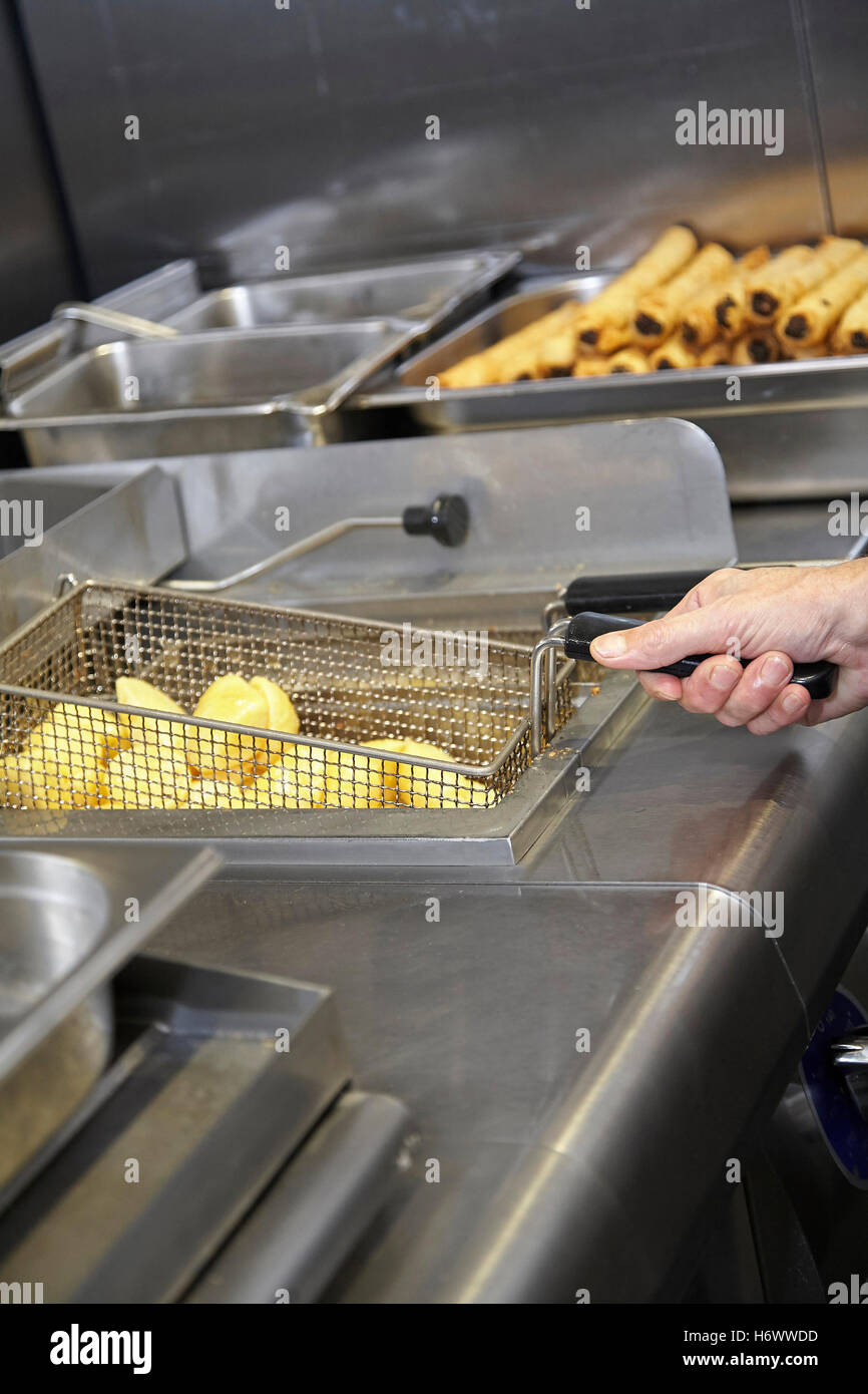 Chef deep frying potatoes in a commercial kitchen in the UK Stock Photo ...