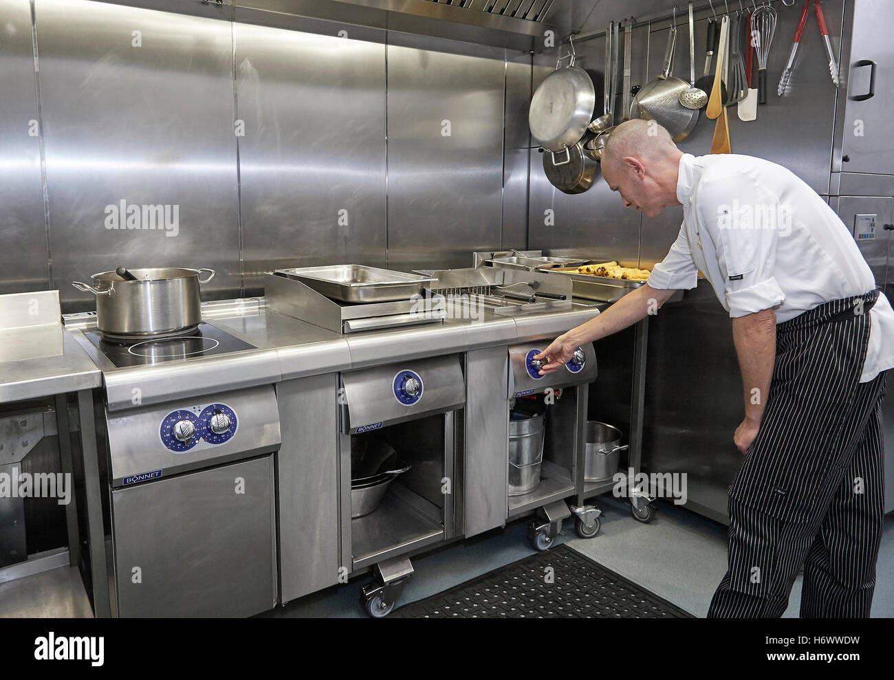 Chef in a commercial kitchen adjusting the cooker Stock Photo - Alamy