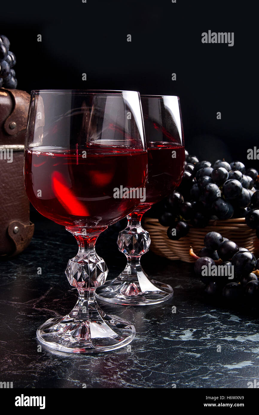 Two glass of red wine on dark marble background. Blue ripe grapes on ...