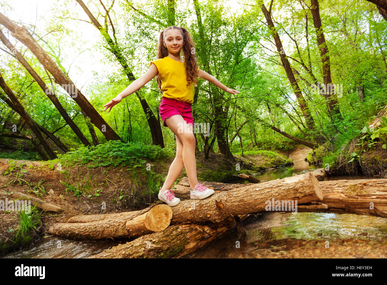 Young girl balancing on a log crossing over river Stock Photo - Alamy