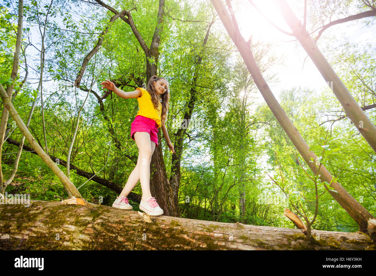 Cute little girl walking on trunk of fallen tree Stock Photo - Alamy