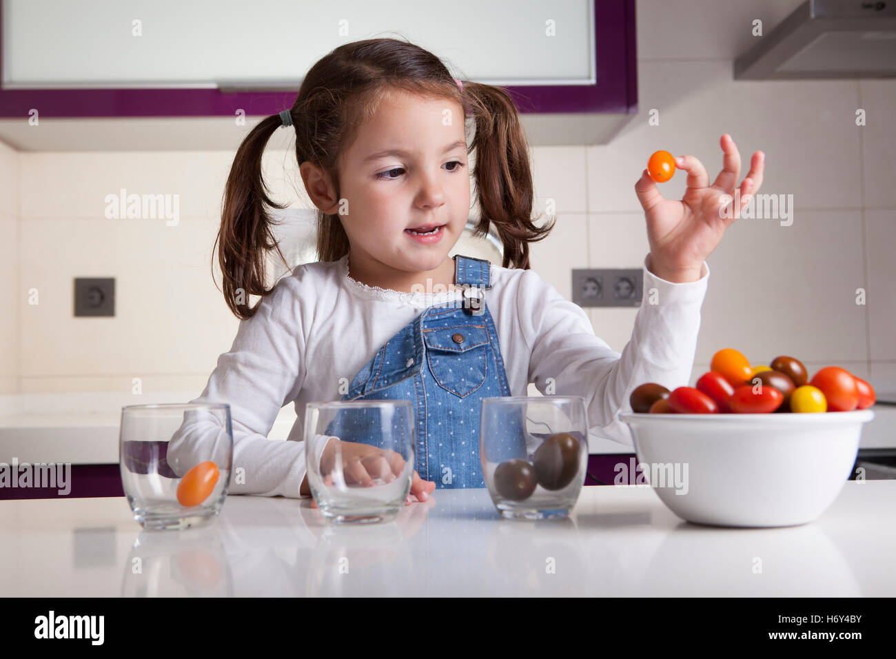 Little girl sorting by colors cherry tomatoes. Education on healthy ...