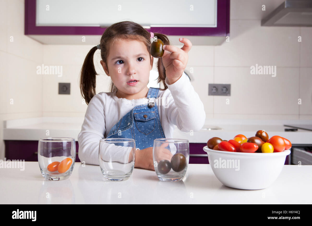 Little girl sorting by colors cherry tomatoes. Education on healthy ...