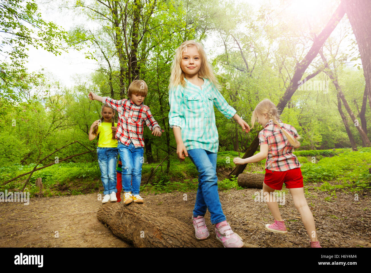 Happy kids walking on log and balancing in forest Stock Photo - Alamy