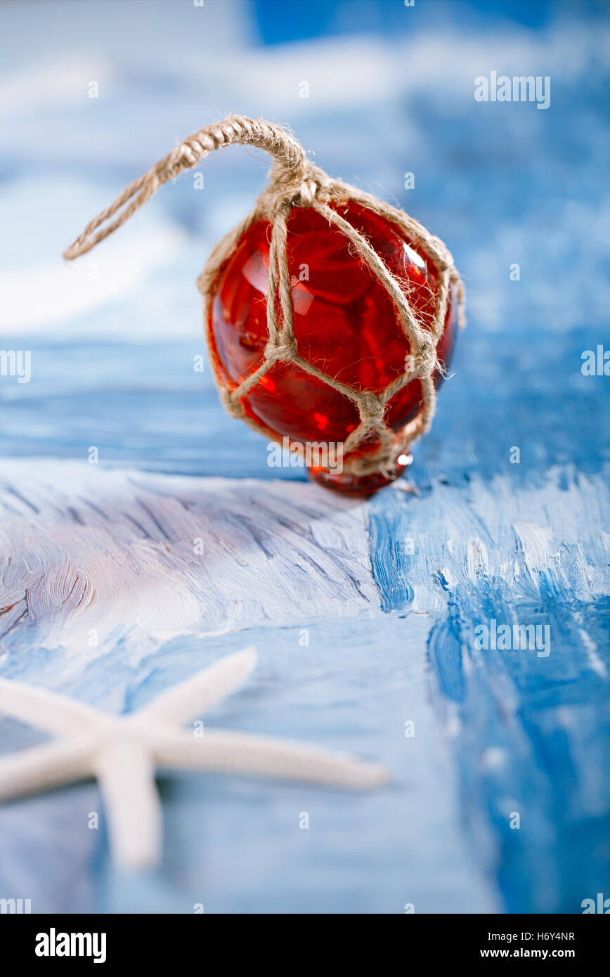 red Glass float with white starfish on blue painted background Stock ...